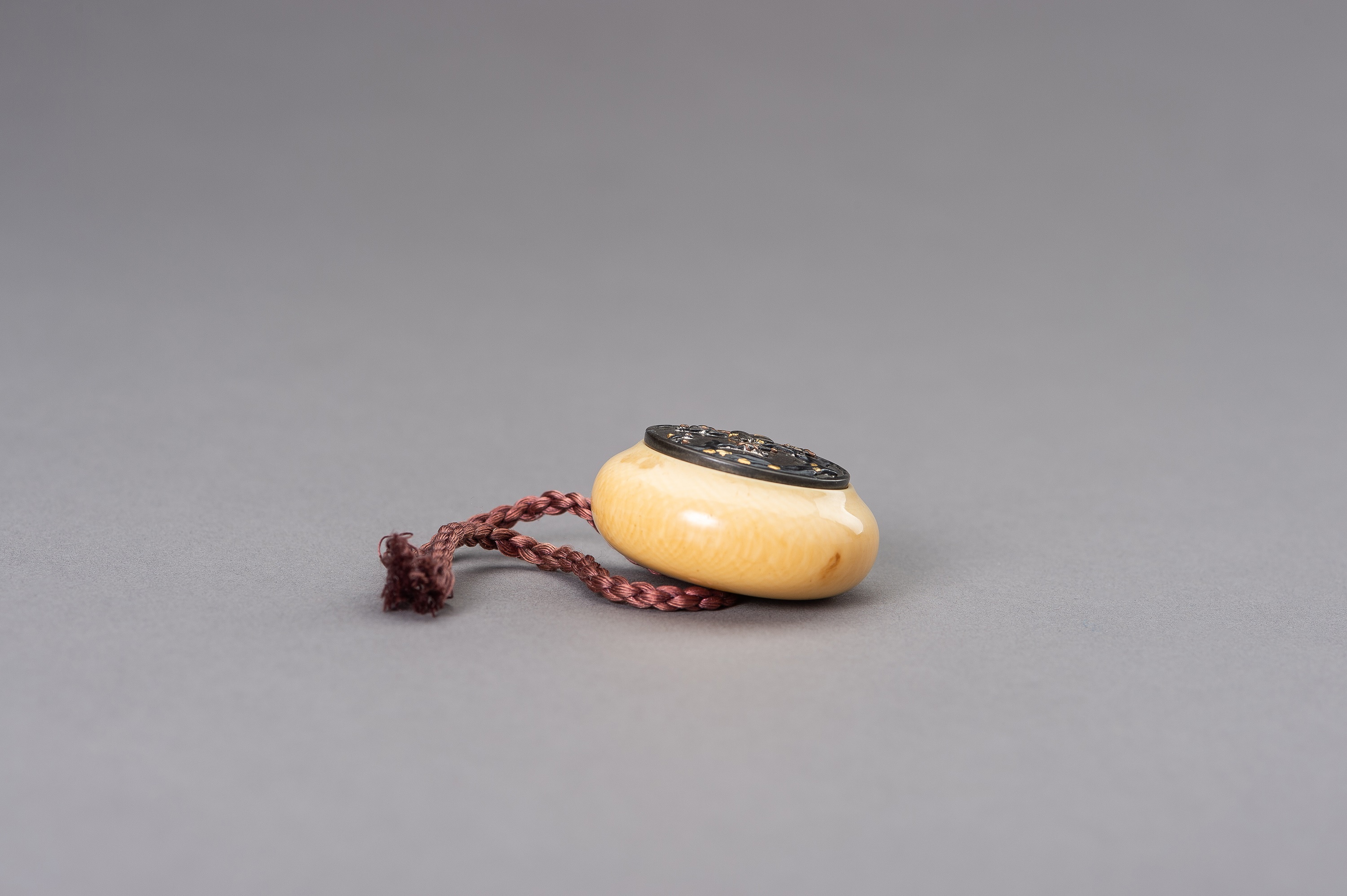 Lot 514 - AN IVORY AND SHIBUICHI KAGAMIBUTA NETSUKE