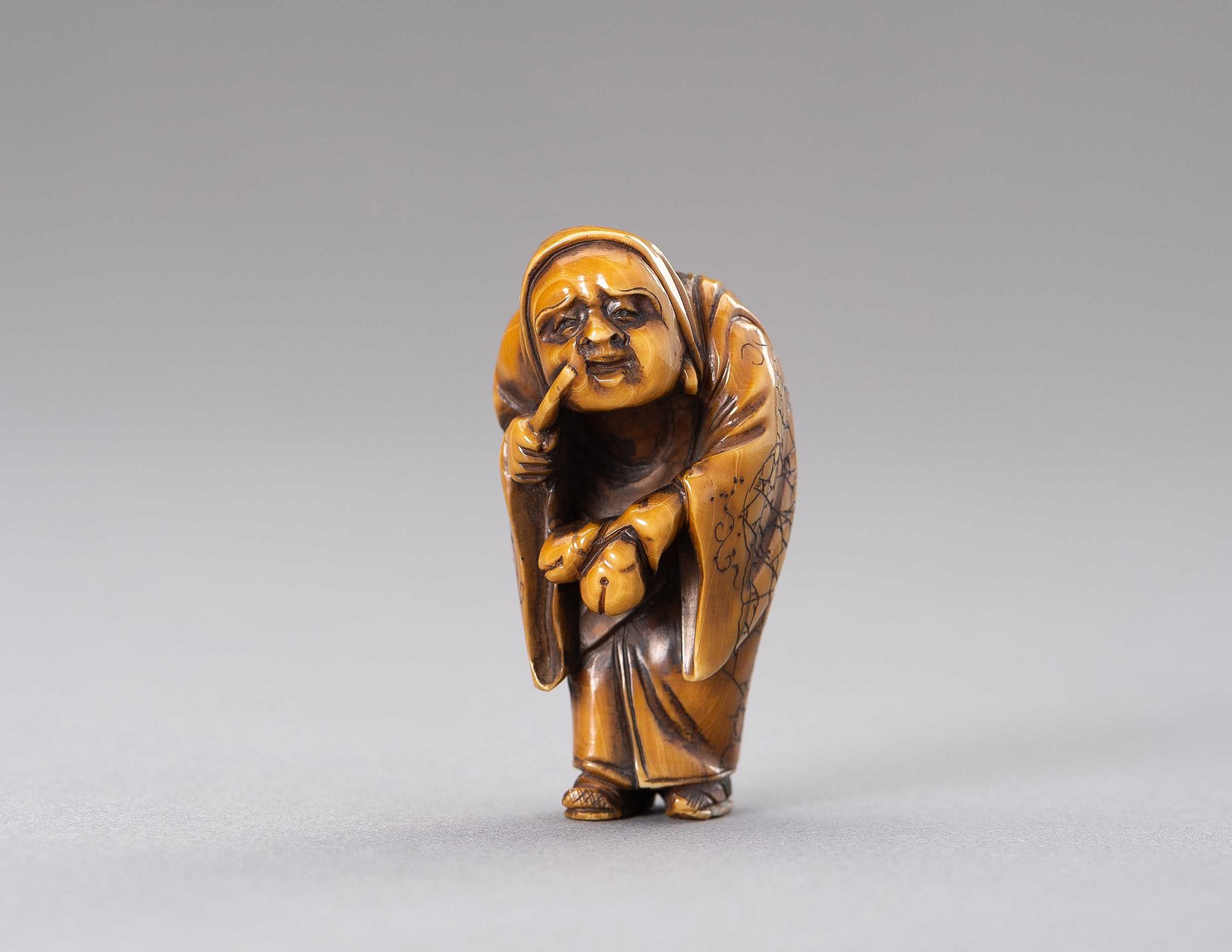 Lot 499 - A STAINED IVORY NETSUKE OF DARUMA