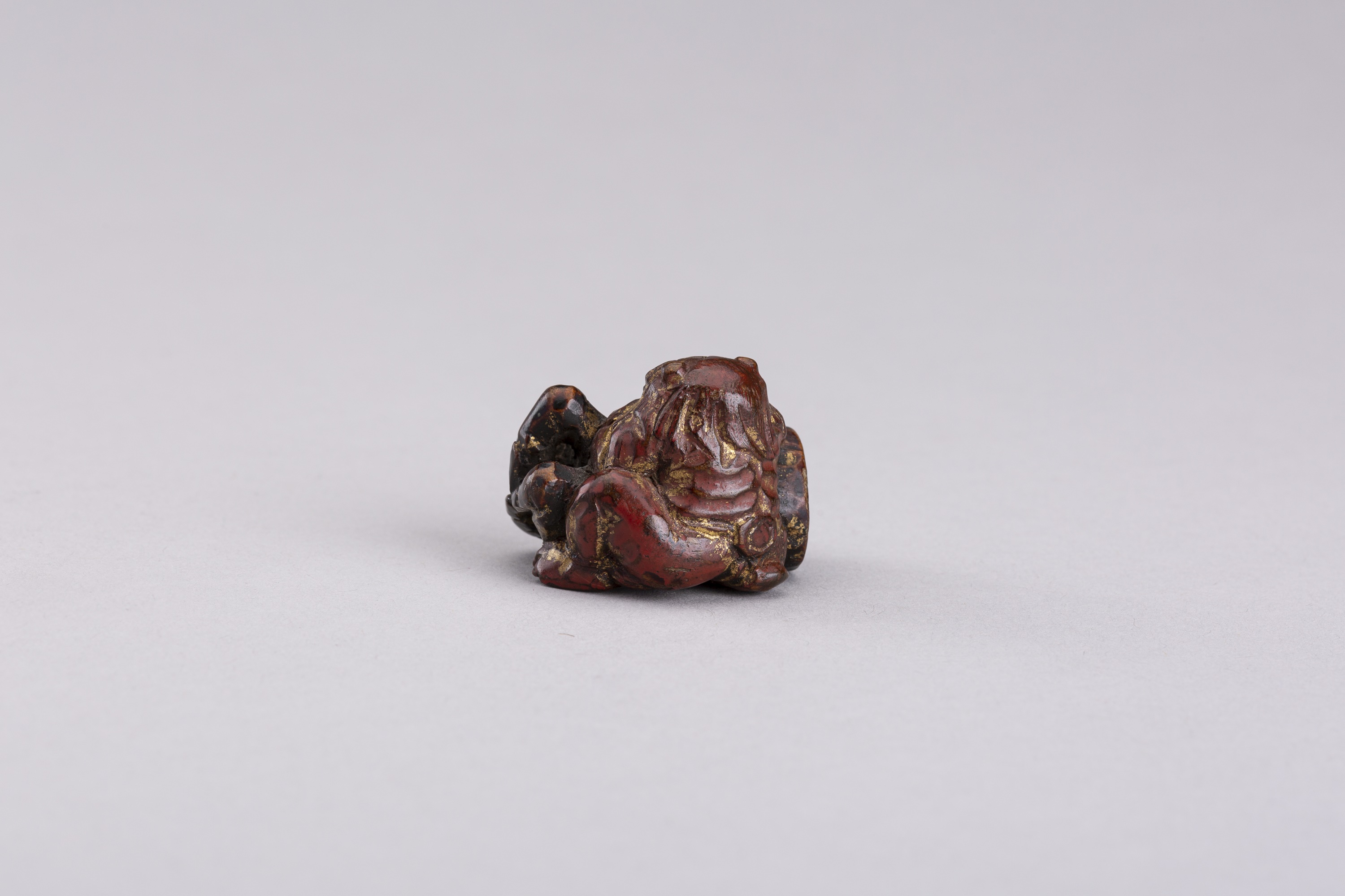 Lot 788 - A LACQUERED WOOD NETSUKE OF AN ONI WITH