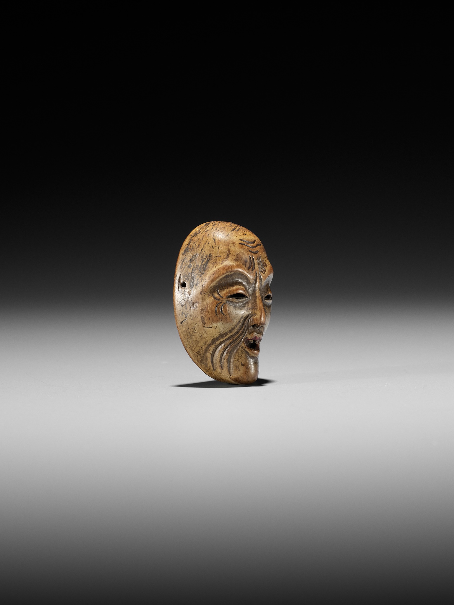 Lot 257 - A LACQUERED WOOD MASK NETSUKE OF KOJO