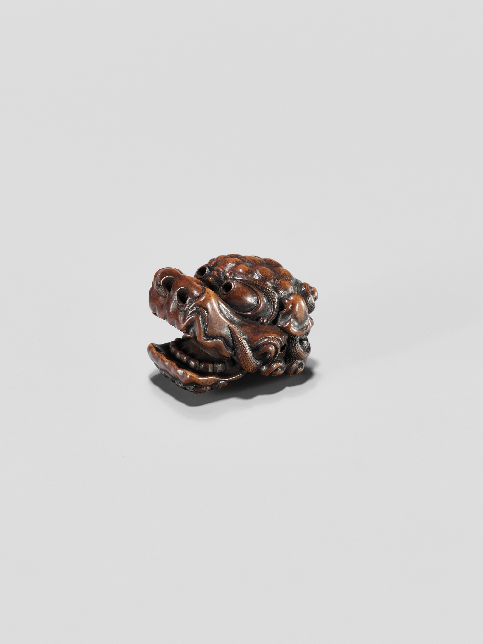 Lot 433 - A WOOD NETSUKE OF A SHISHI MASK WITH MOVABLE