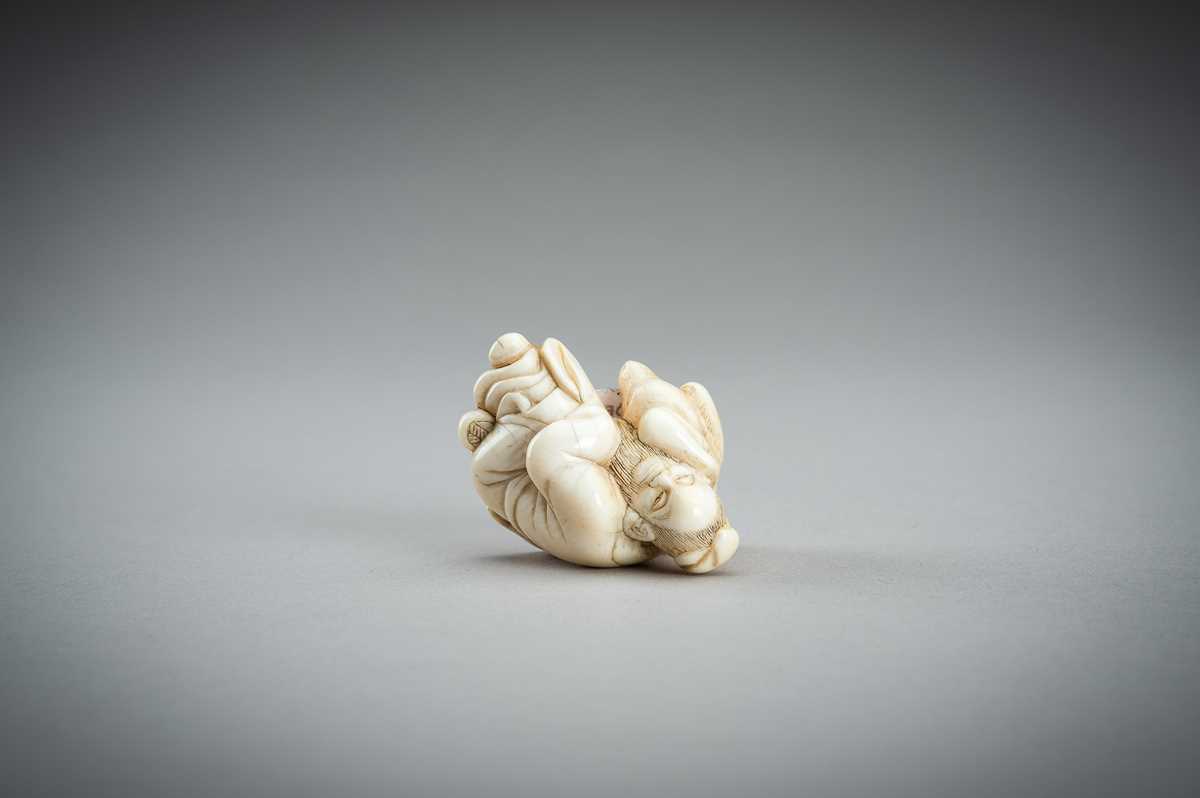 Lot 876 - AN IVORY NETSUKE OF A SAGE RECLINING ON A