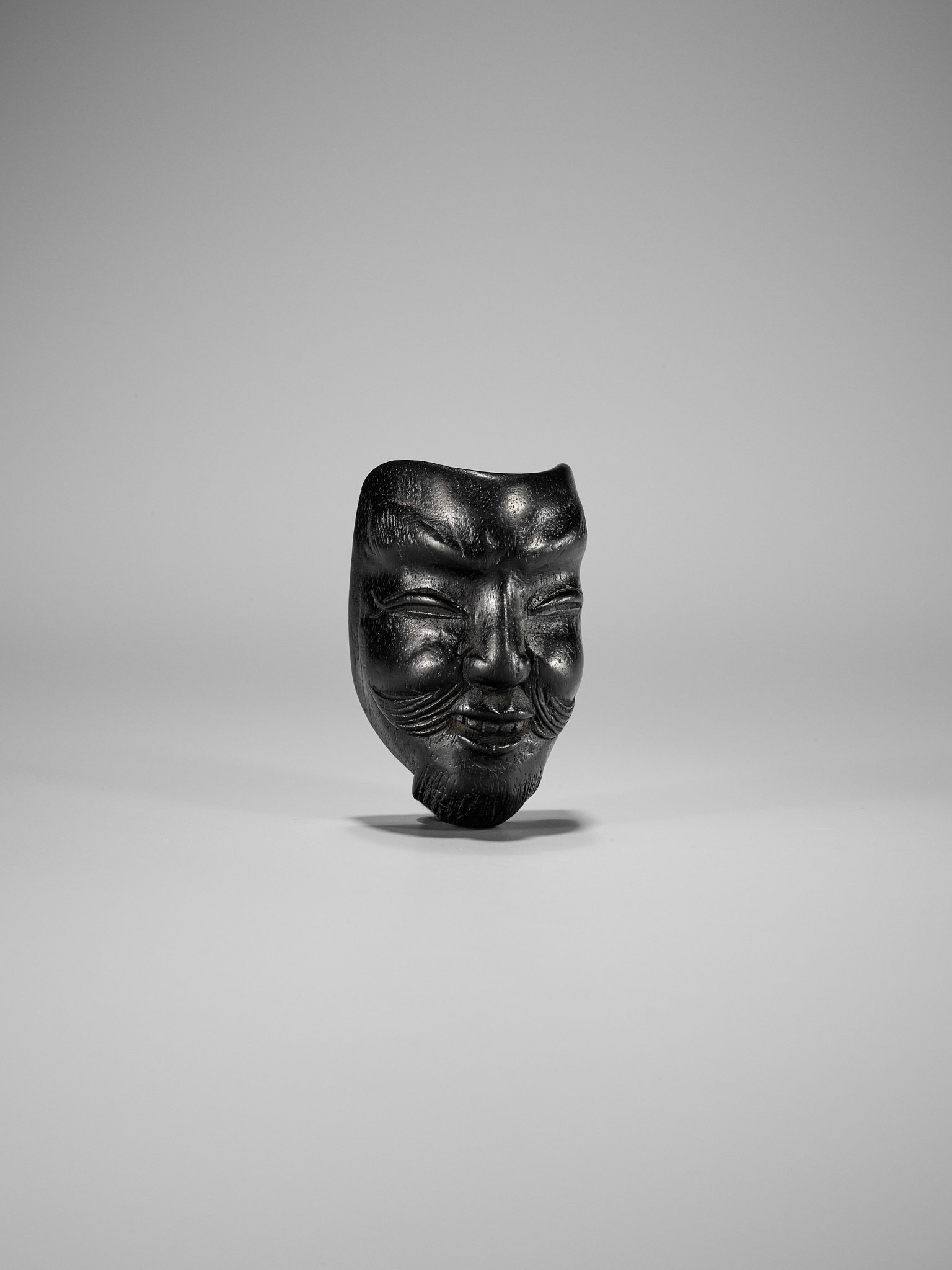 Lot 249 - OKATOMO: A VERY RARE EBONY WOOD MASK NETSUKE