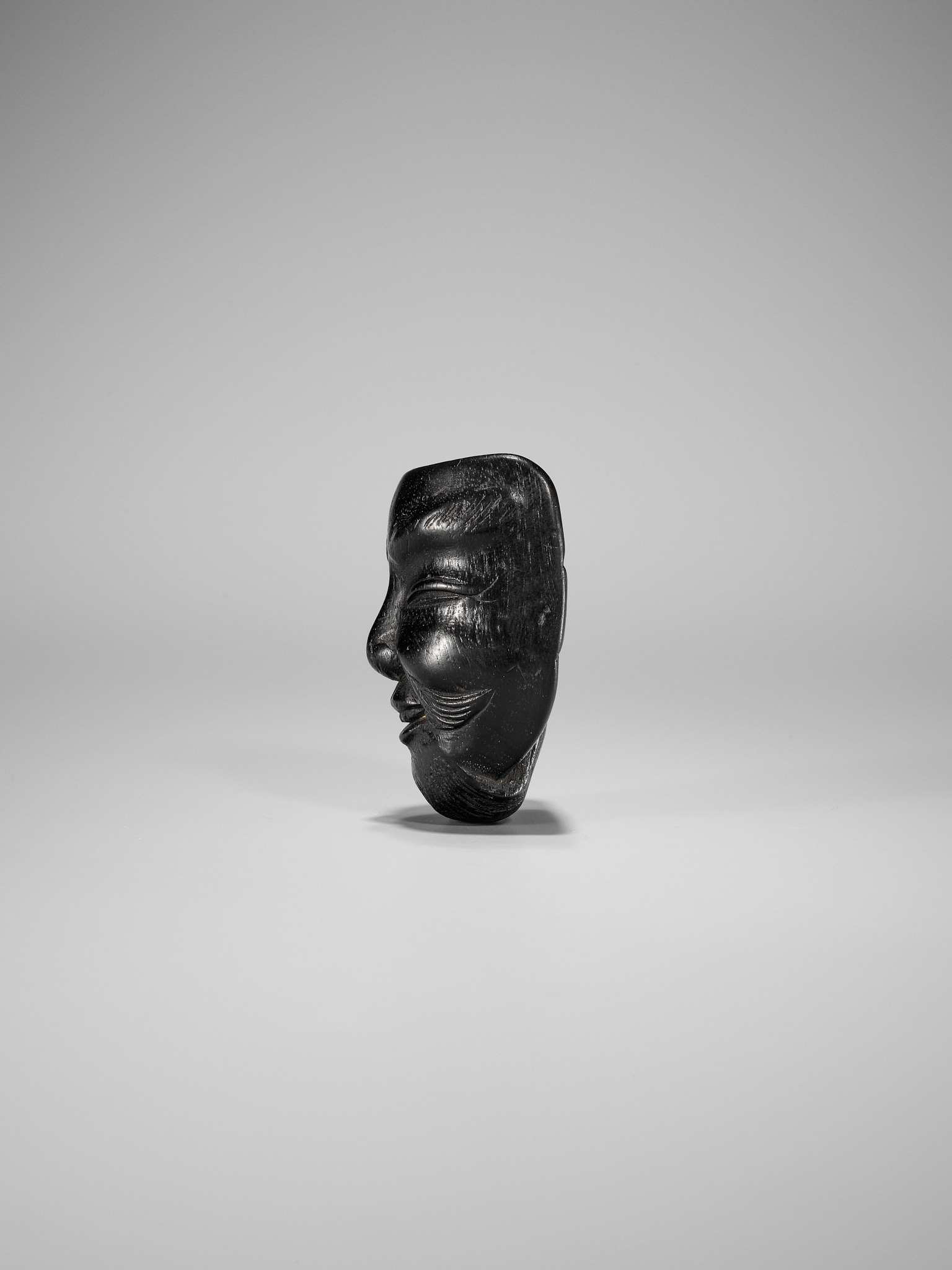 Lot 249 - OKATOMO: A VERY RARE EBONY WOOD MASK NETSUKE