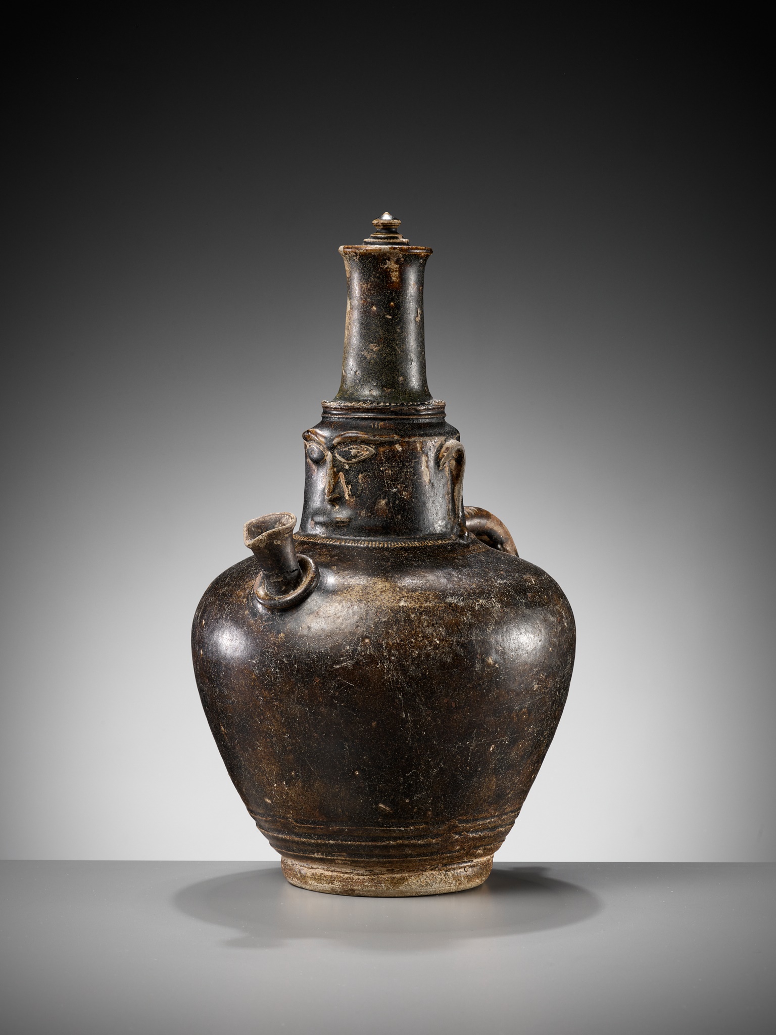 Lot 702 - A BROWN-GLAZED STONEWARE JAR WITH A HUMAN