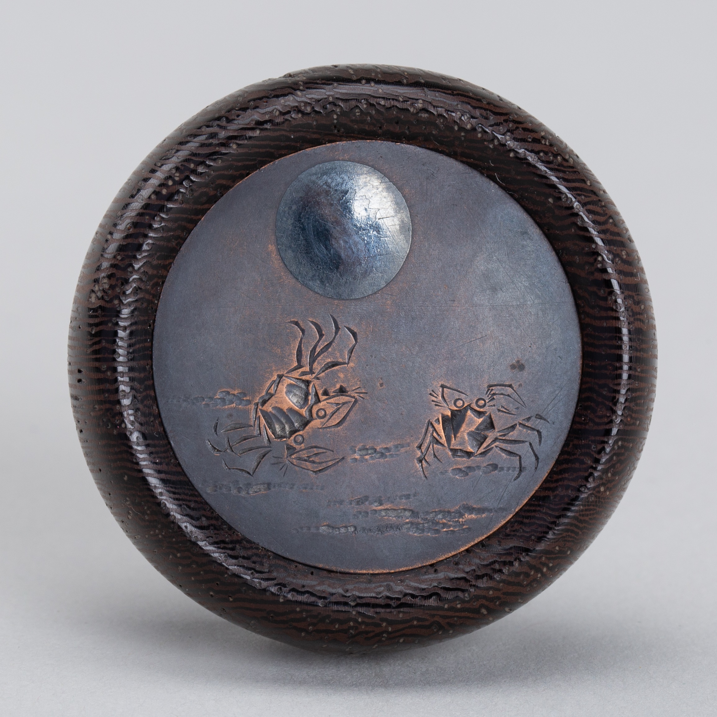 Lot 442 - A WOOD KAGAMIBUTA NETSUKE WITH SHIBUICHI