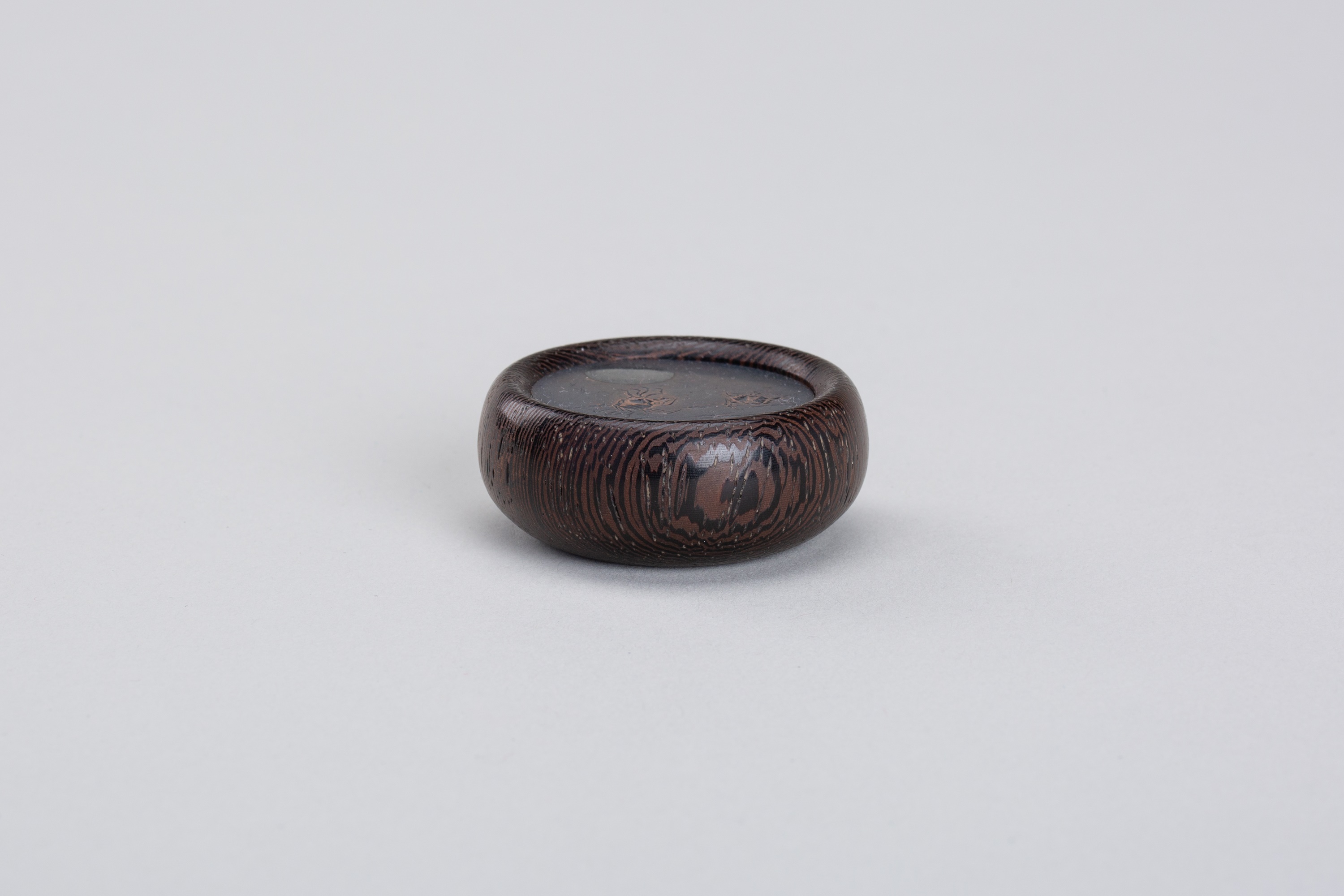Lot 442 - A WOOD KAGAMIBUTA NETSUKE WITH SHIBUICHI