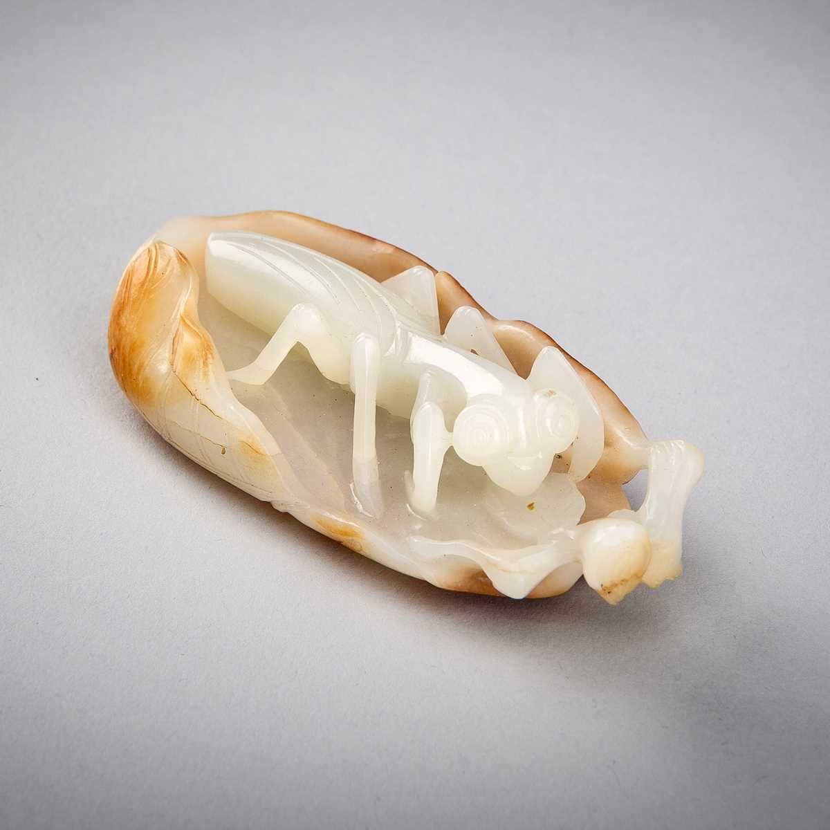 Lot 903 - A PALE CELADON AND RUSSET JADE ‘PRAYING