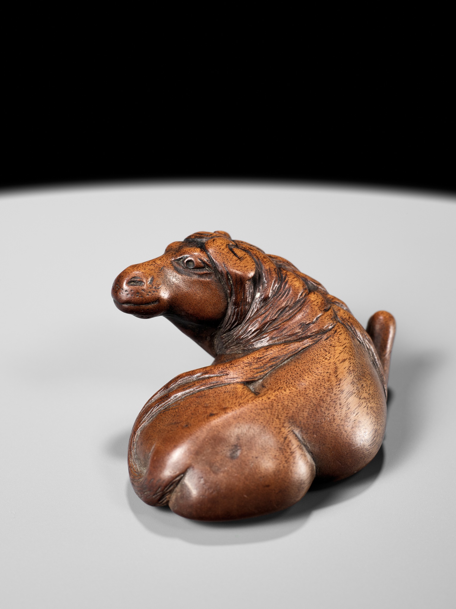 Lot 107 - YASUTADA: A RARE WOOD NETSUKE OF A RECUMBENT