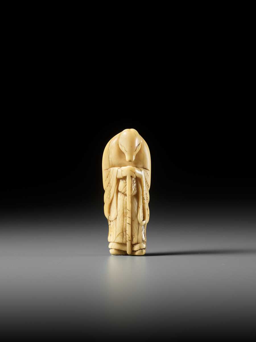 Lot 61 - A FINE IVORY NETSUKE OF A FOX PRIEST