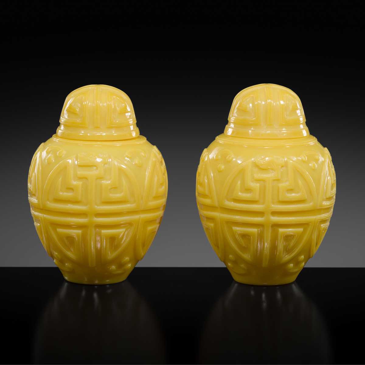 Lot 113 - A RARE PAIR OF CARVED YELLOW GLASS JARS AND