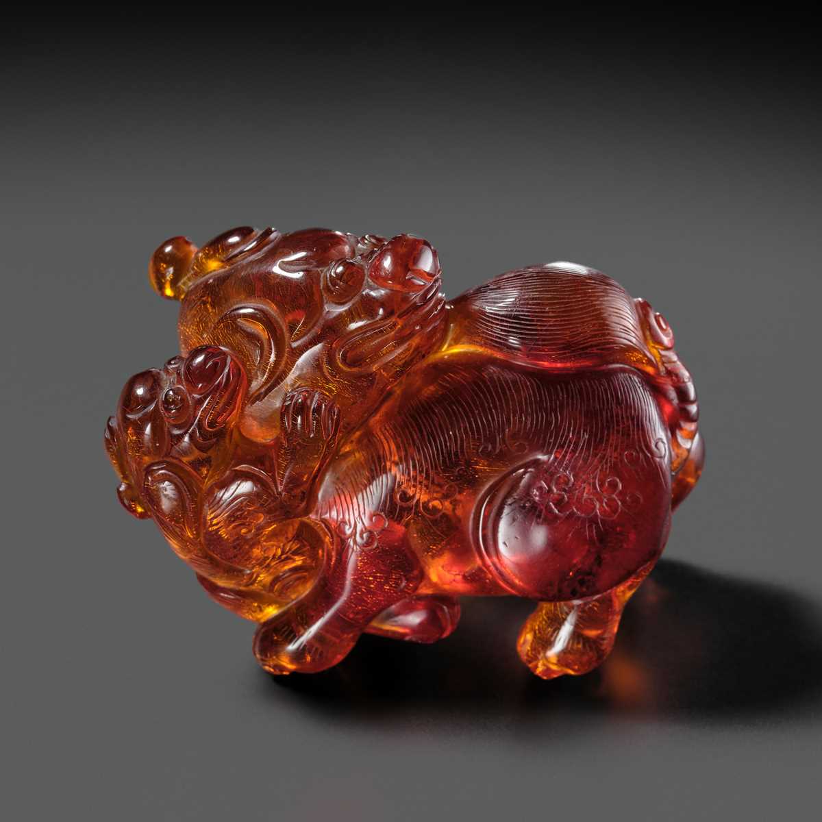 Lot 119 - AN AMBER CARVING OF A MYTHICAL BEAST GROUP,