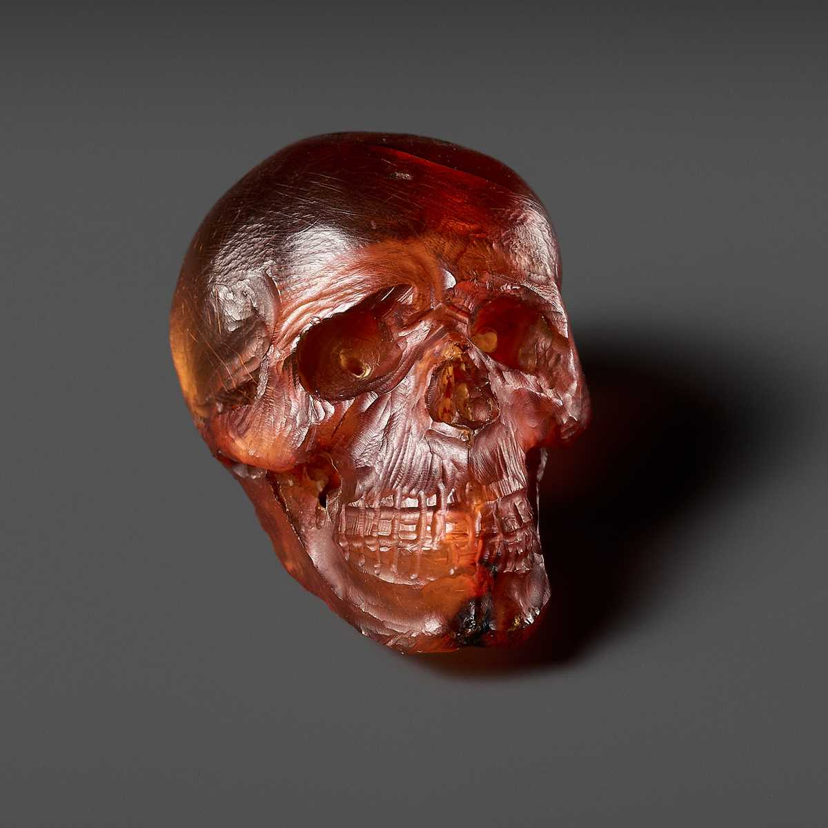 Lot 349 - A RARE CARVED AMBER NETSUKE OF A SKULL