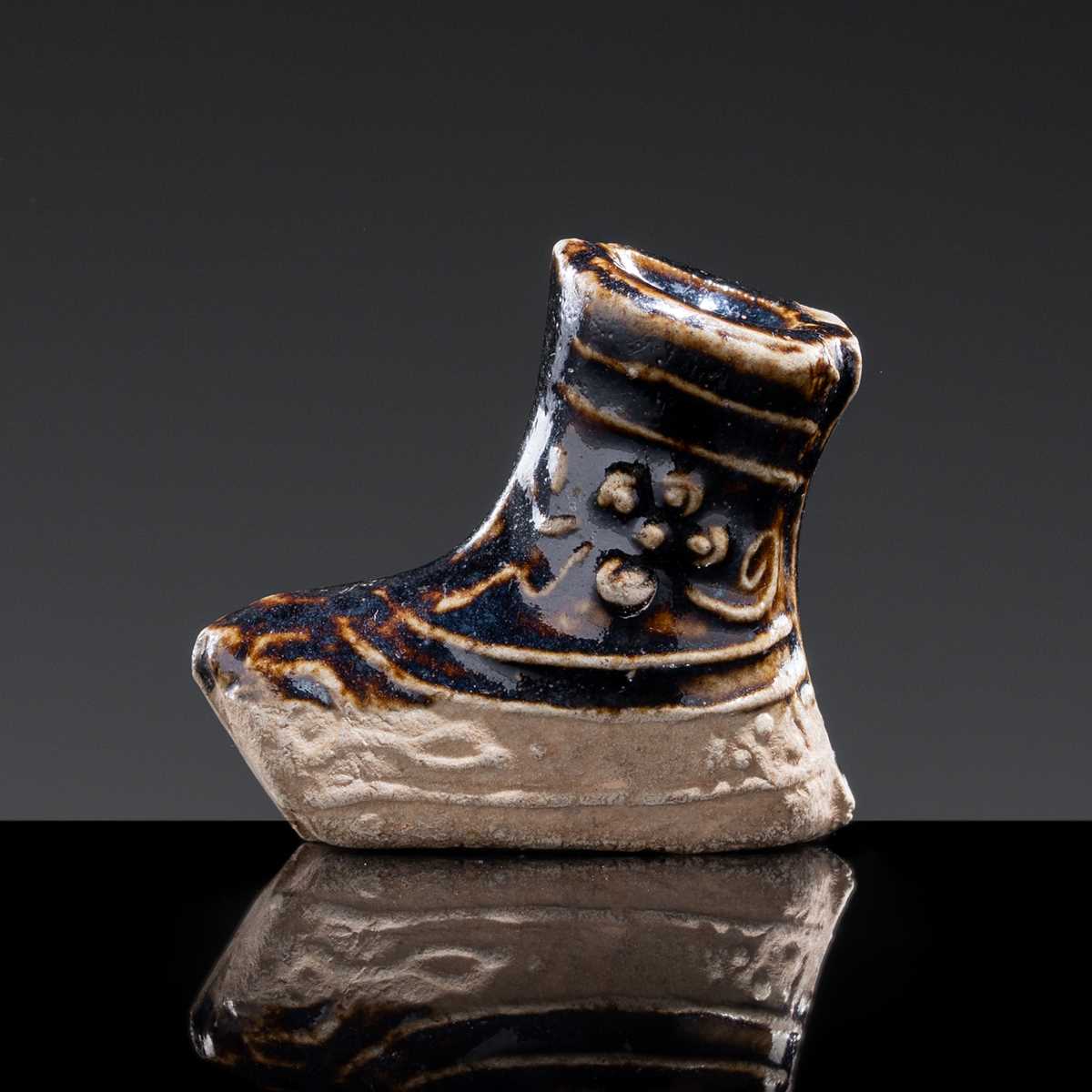 Lot 104 - A CIZHOU POTTERY FIGURE OF A BOOT, JIN