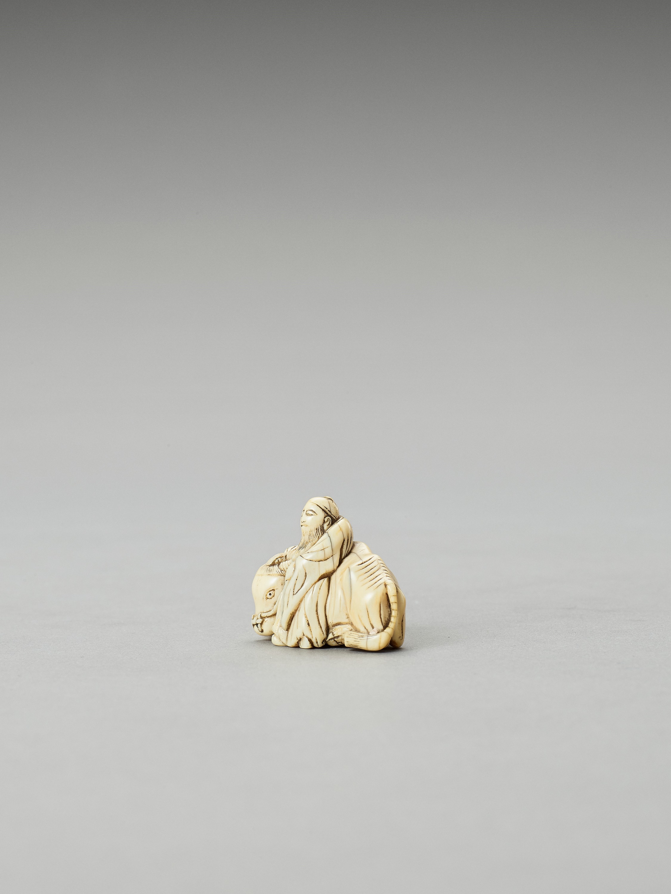 Lot 343 - AN EARLY IVORY NETSUKE OF ROSHI WITH OX