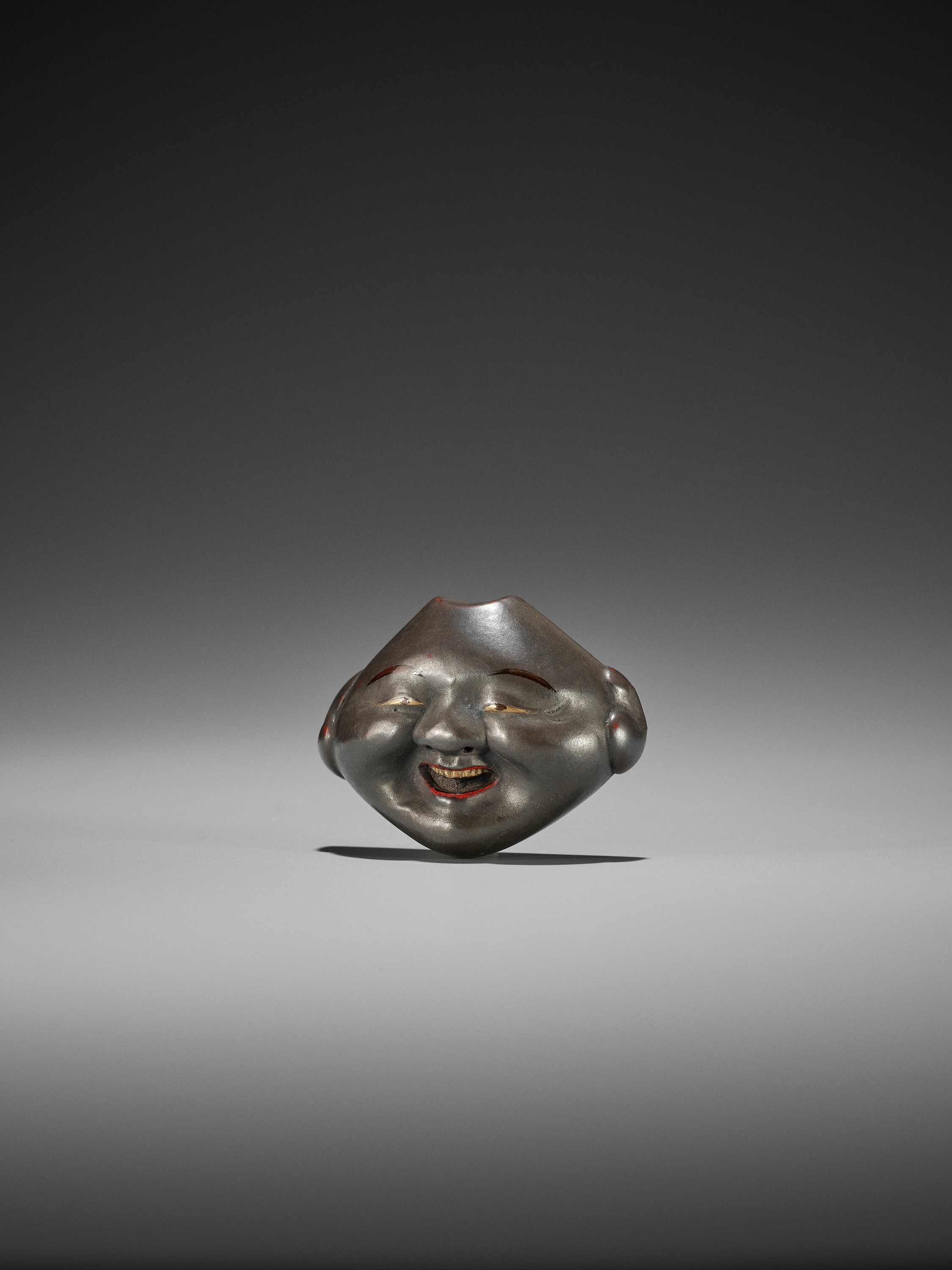 Lot 87 - SHOMAN: A RARE LACQUERED MASK NETSUKE OF