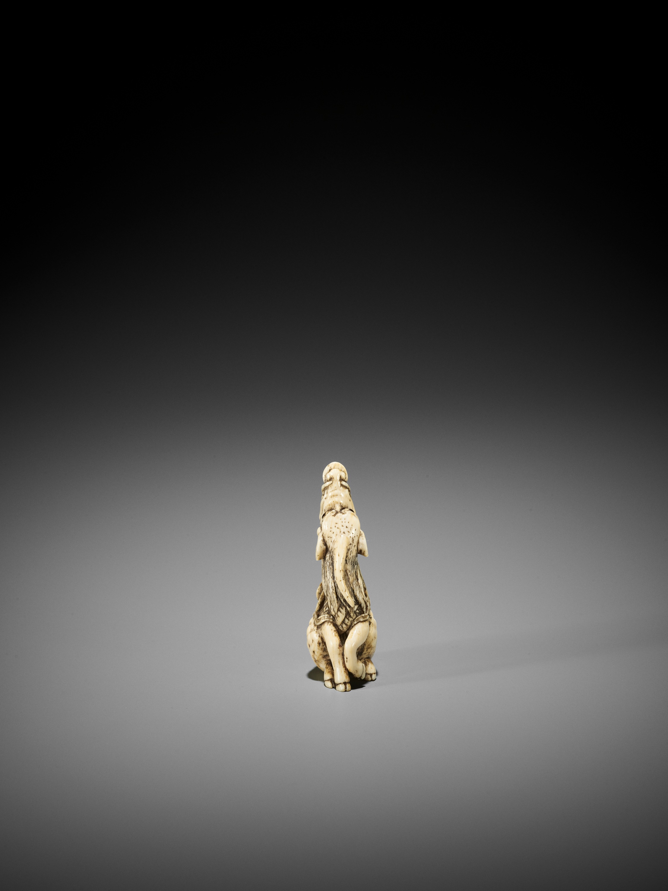Lot 191 - AN IVORY NETSUKE OF A BAYING KIRIN IN THE