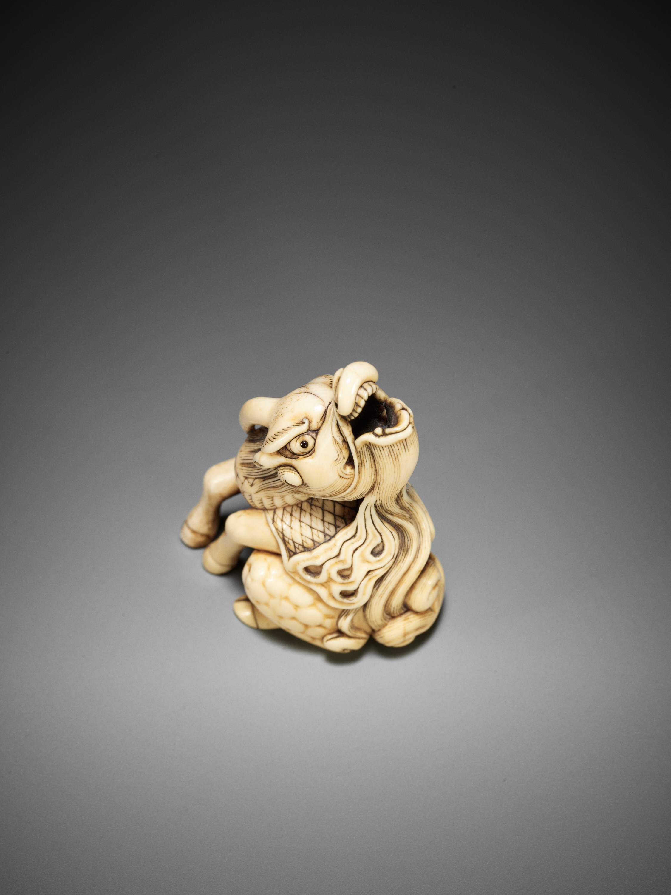 Lot 50 - A POWERFUL IVORY NETSUKE OF A BAYING KIRIN,