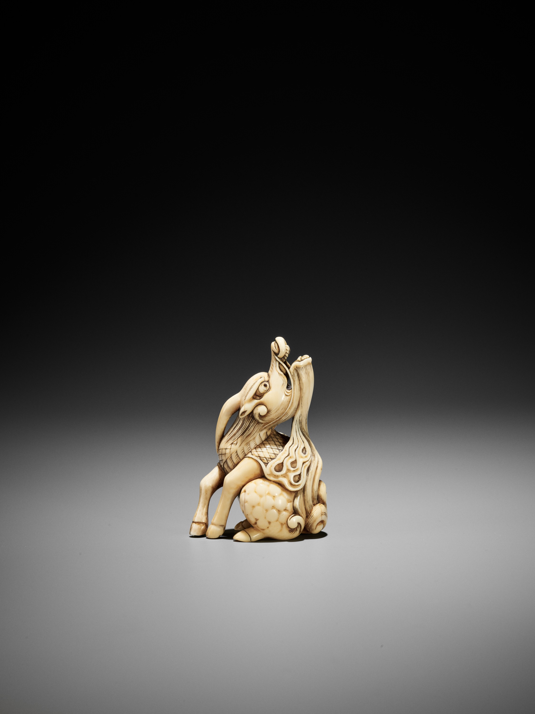 Lot 50 - A POWERFUL IVORY NETSUKE OF A BAYING KIRIN,